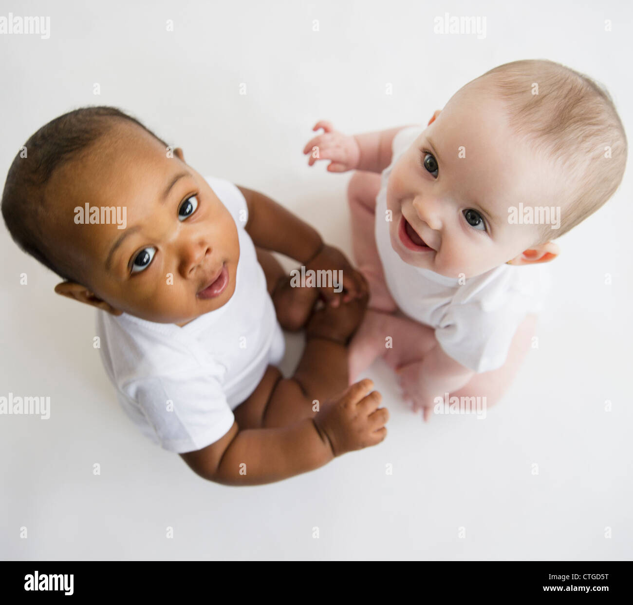 Babies sitting together on floor Stock Photo - Alamy