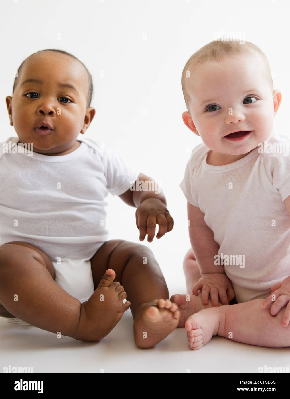 Babies sitting together on floor Stock Photo - Alamy