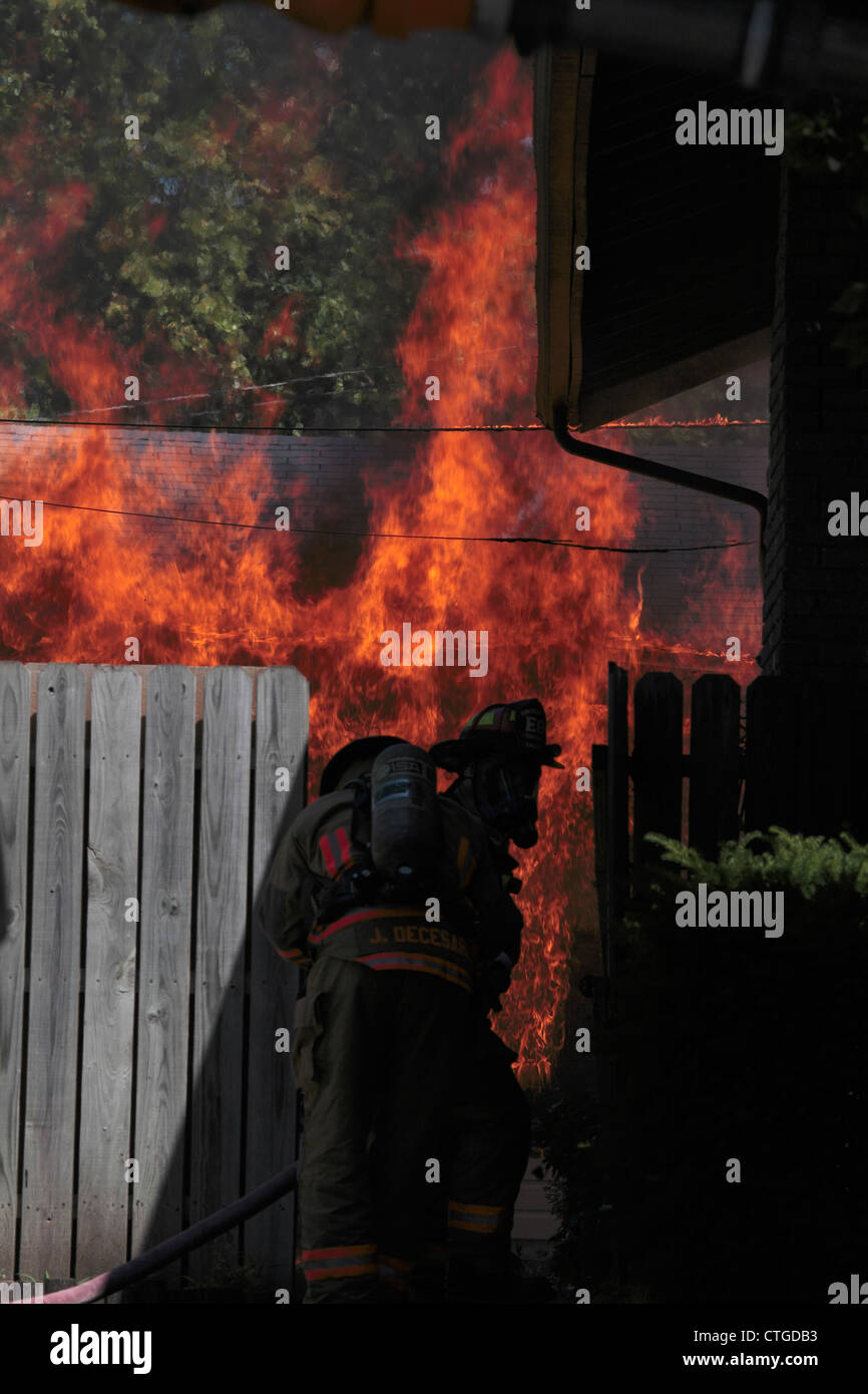 Firefighters are silhouetted by the large orange flames of a fire ...