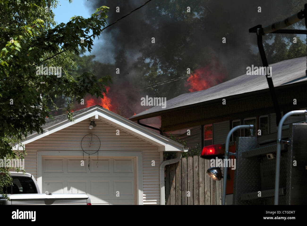 Flames shoot up behind small wooden buildings from a garage fire Stock ...