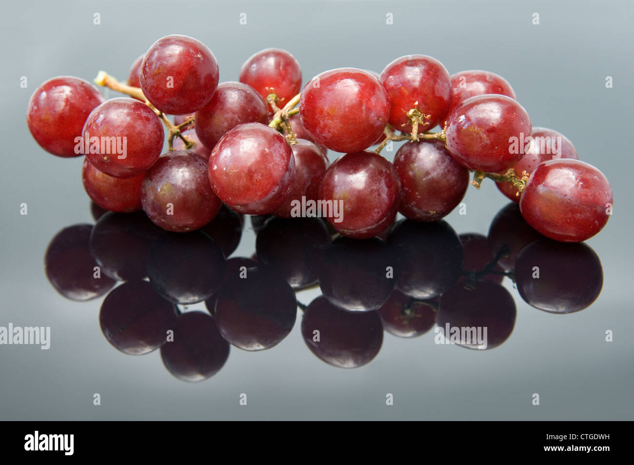 Small bunch of grapes on reflective black background Stock Photo - Alamy