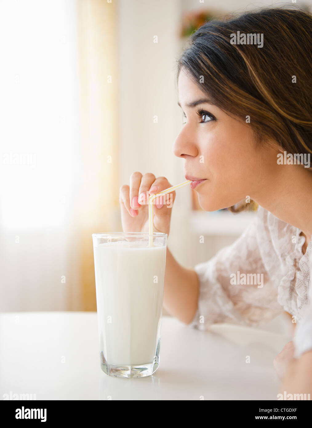 Hispanic woman drinking milk through straw Stock Photo - Alamy