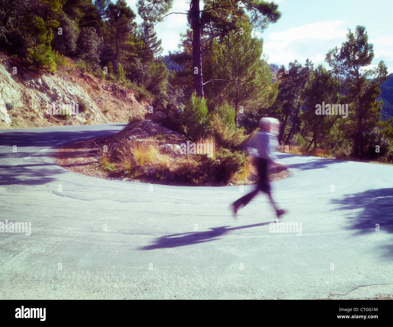 Blurred figure of man running around u-bend in empty road Stock Photo ...