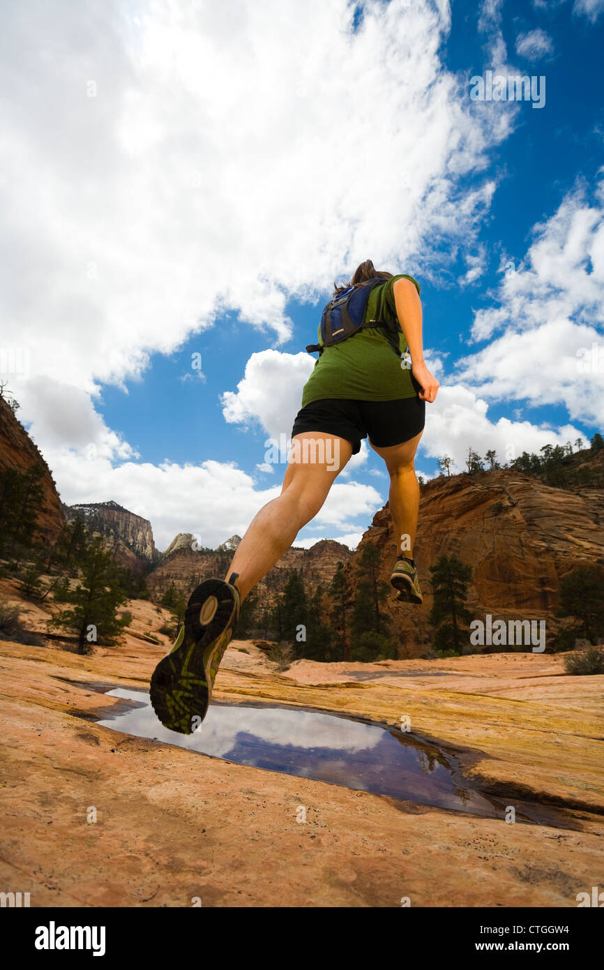 Persian woman jumping over canyon puddle Stock Photo - Alamy