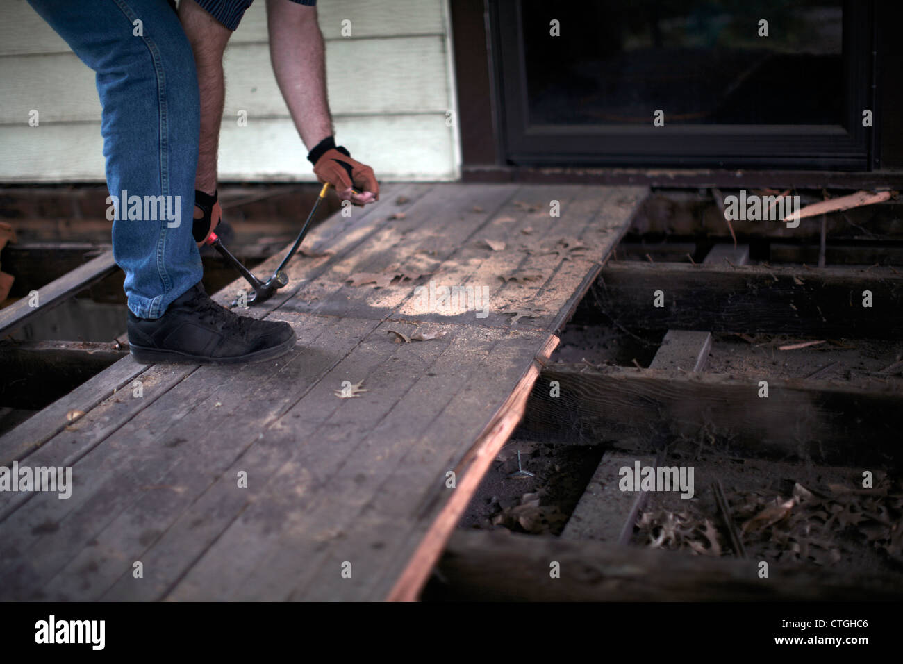 Man using hammer and prybar to remove porch decking planks Stock Photo ...