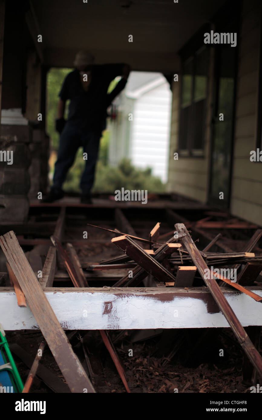 Broken boards lay on the old framing of a porch being demolished as a ...