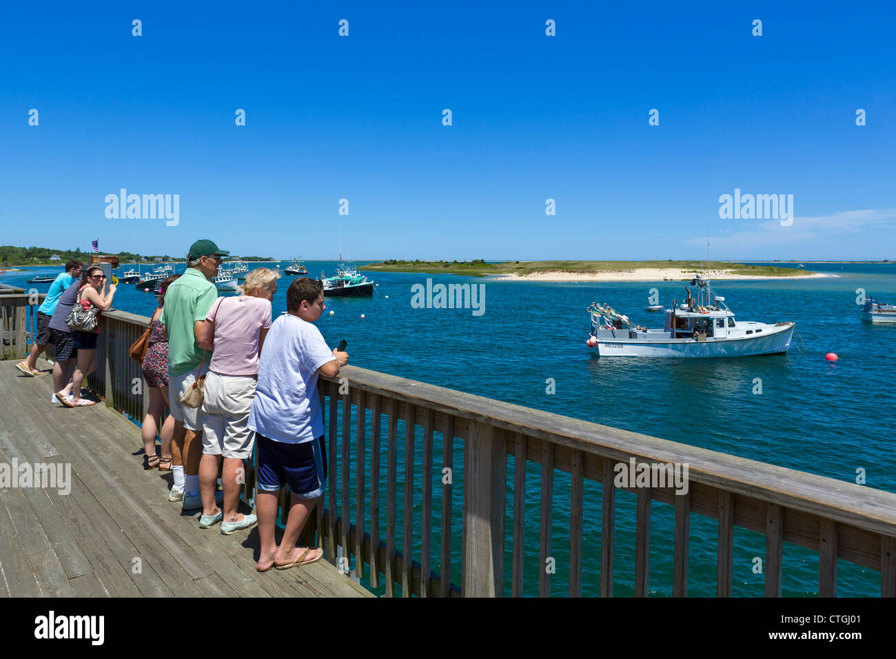 Tourists on terrace overlooking the fishing harbour in Chatham, Cape ...