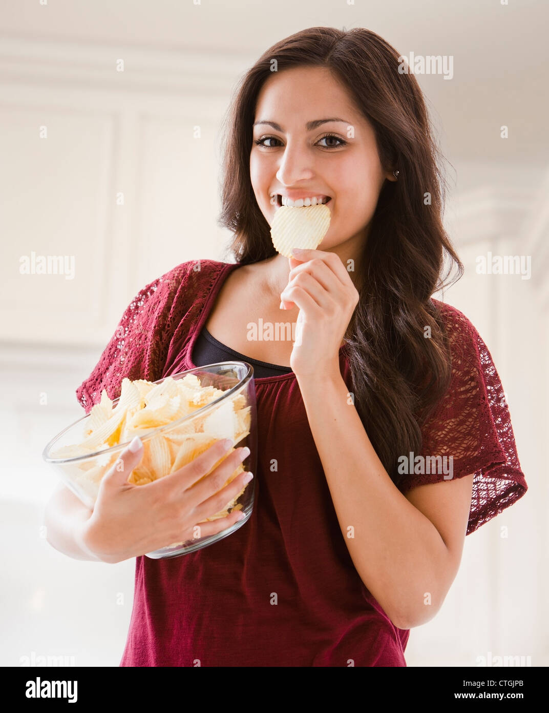 Mixed race woman eating potato chips Stock Photo - Alamy