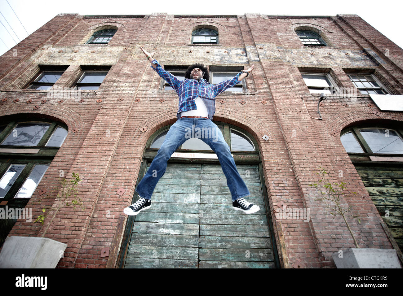 Black man jumping next to urban building Stock Photo - Alamy