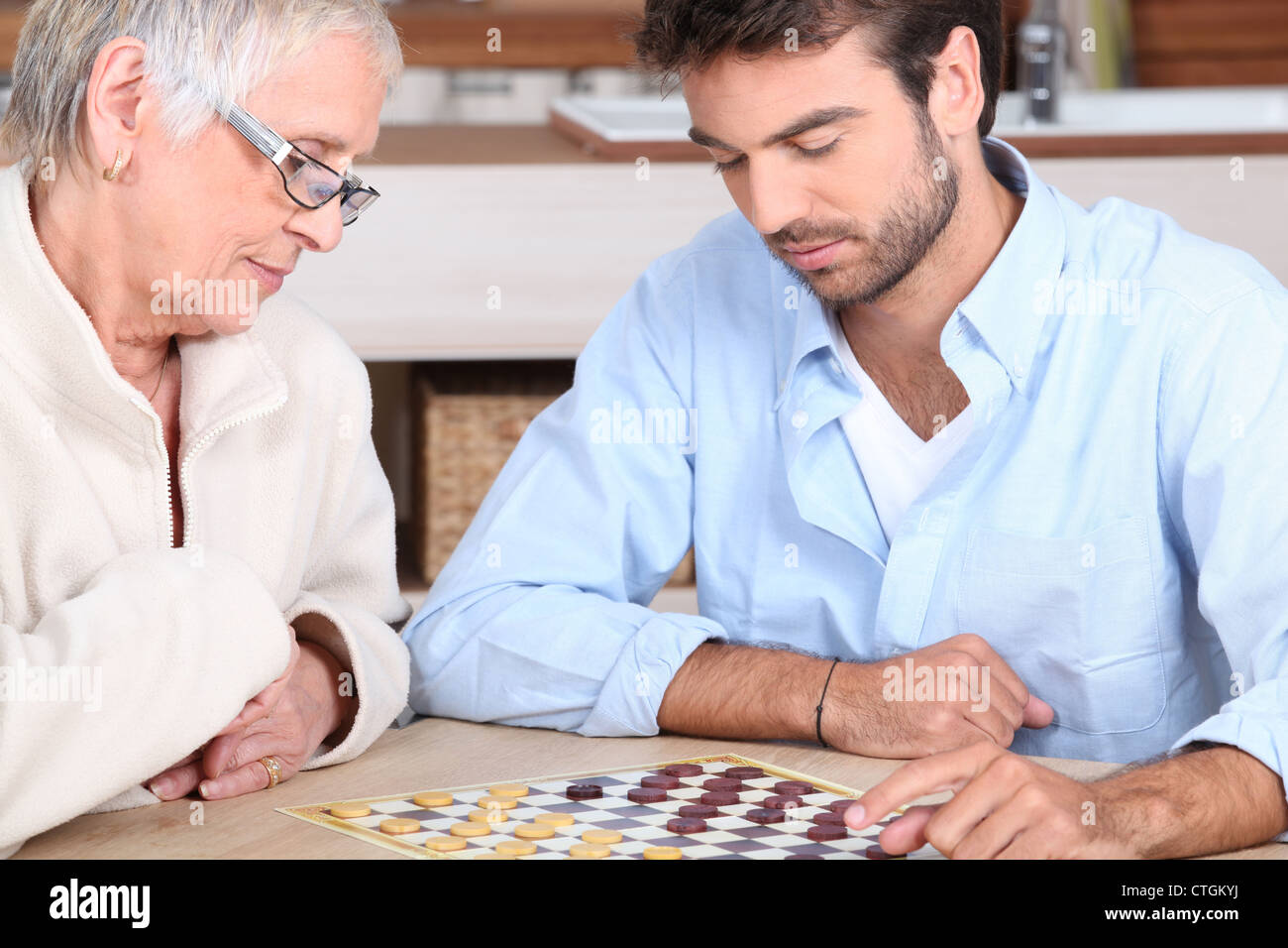 Senior woman and young man playing checkers Stock Photo - Alamy