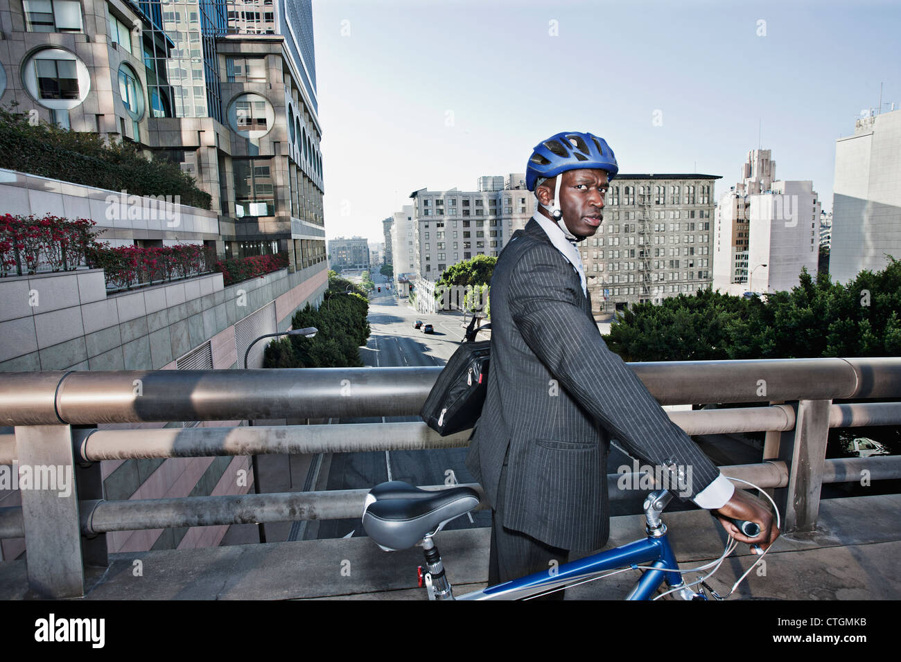 Businessman pushing bicycle over urban bridge Stock Photo - Alamy
