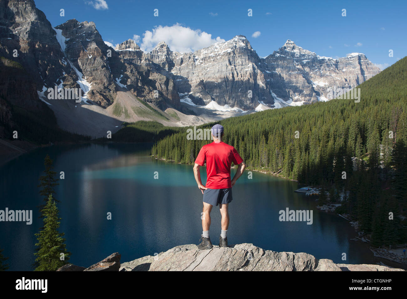 Male Standing On Cliff Lookout Overlooking A Lake And Mountain Range ...