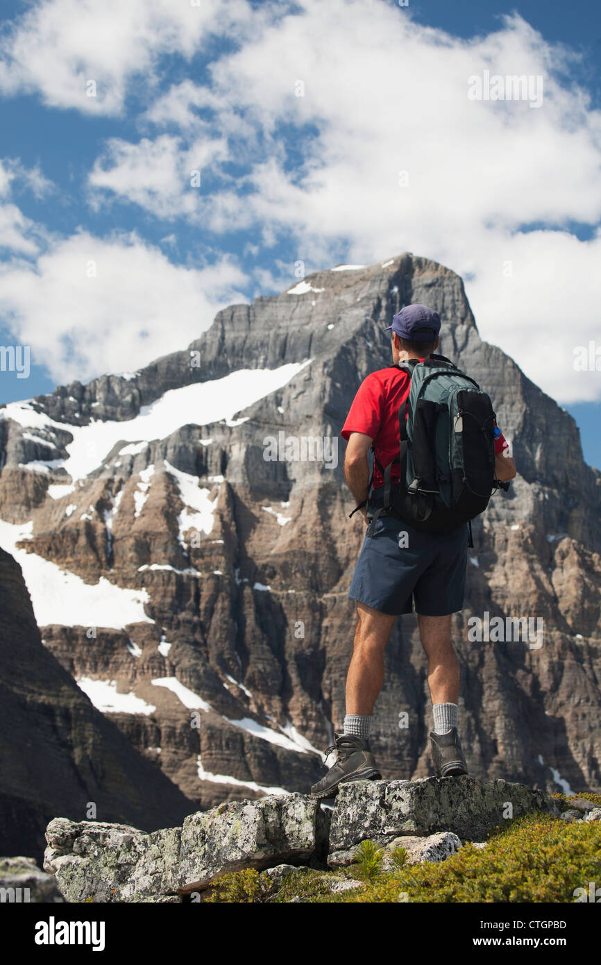 Male Hiker With A Backpack On Cliff Lookout Overlooking A Mountain Face ...