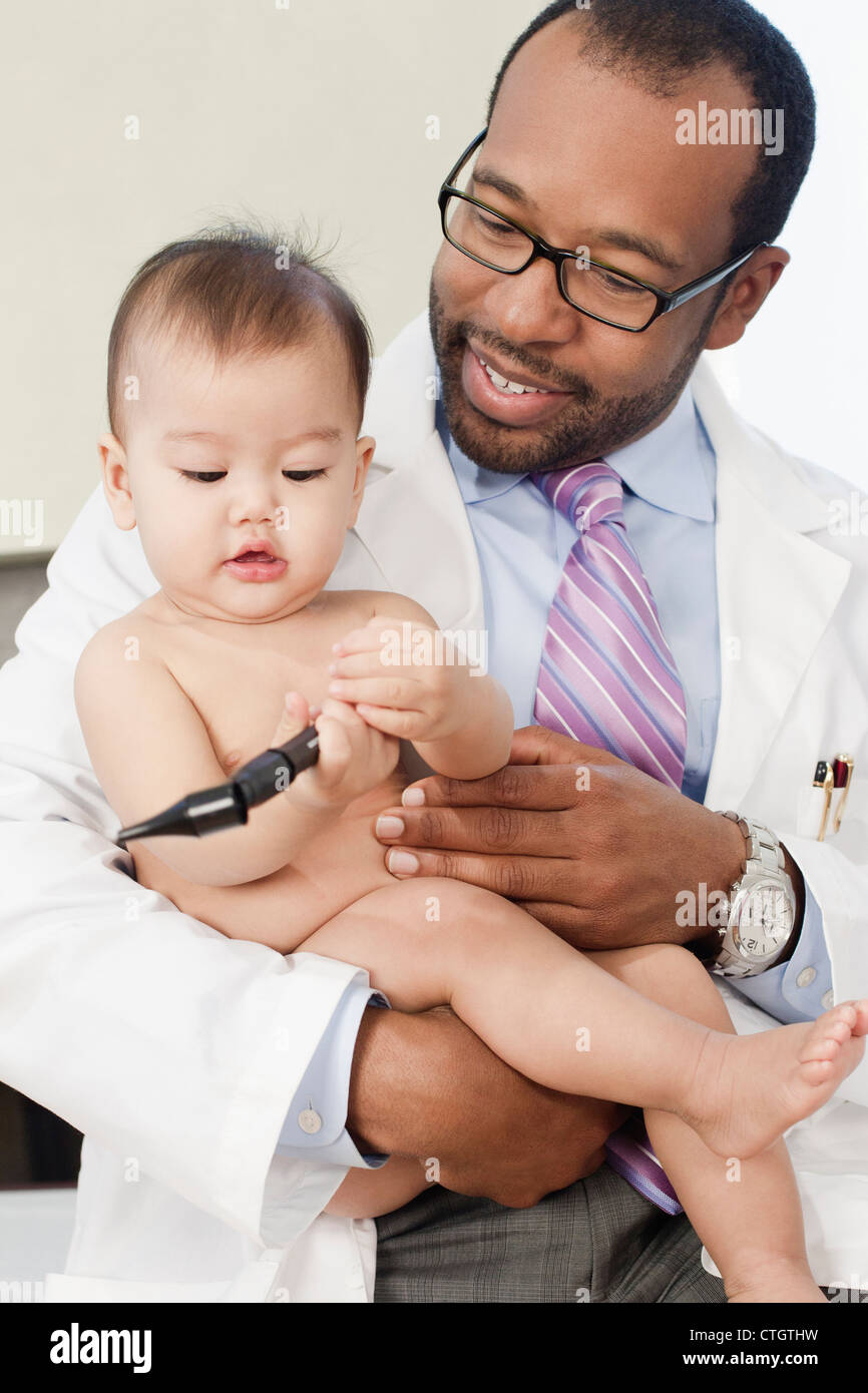 Doctor holding baby in doctor's office Stock Photo - Alamy
