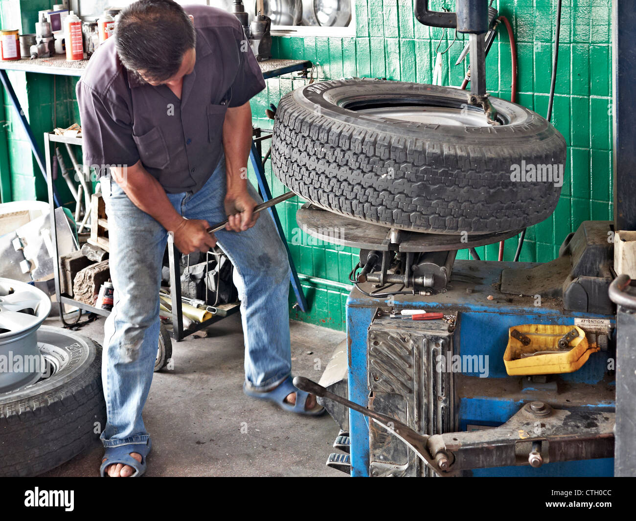 Tyre change Mechanic using machinery and lever to change a car tire ...