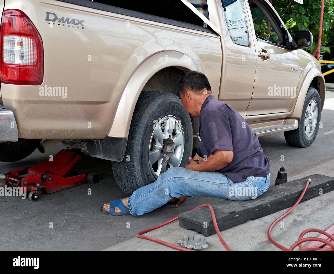 Wheel change. Mechanic changing a car wheel with hydraulic hoist ...