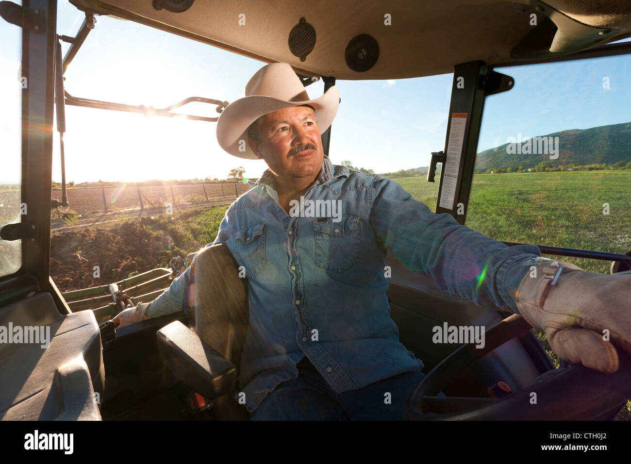 Hispanic man driving tractor Stock Photo - Alamy