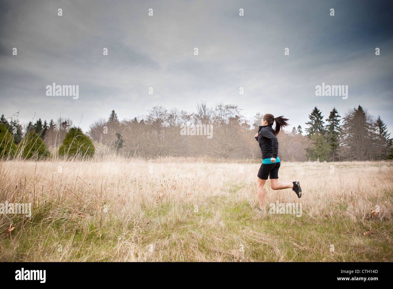 Asian woman jogging in field Stock Photo - Alamy