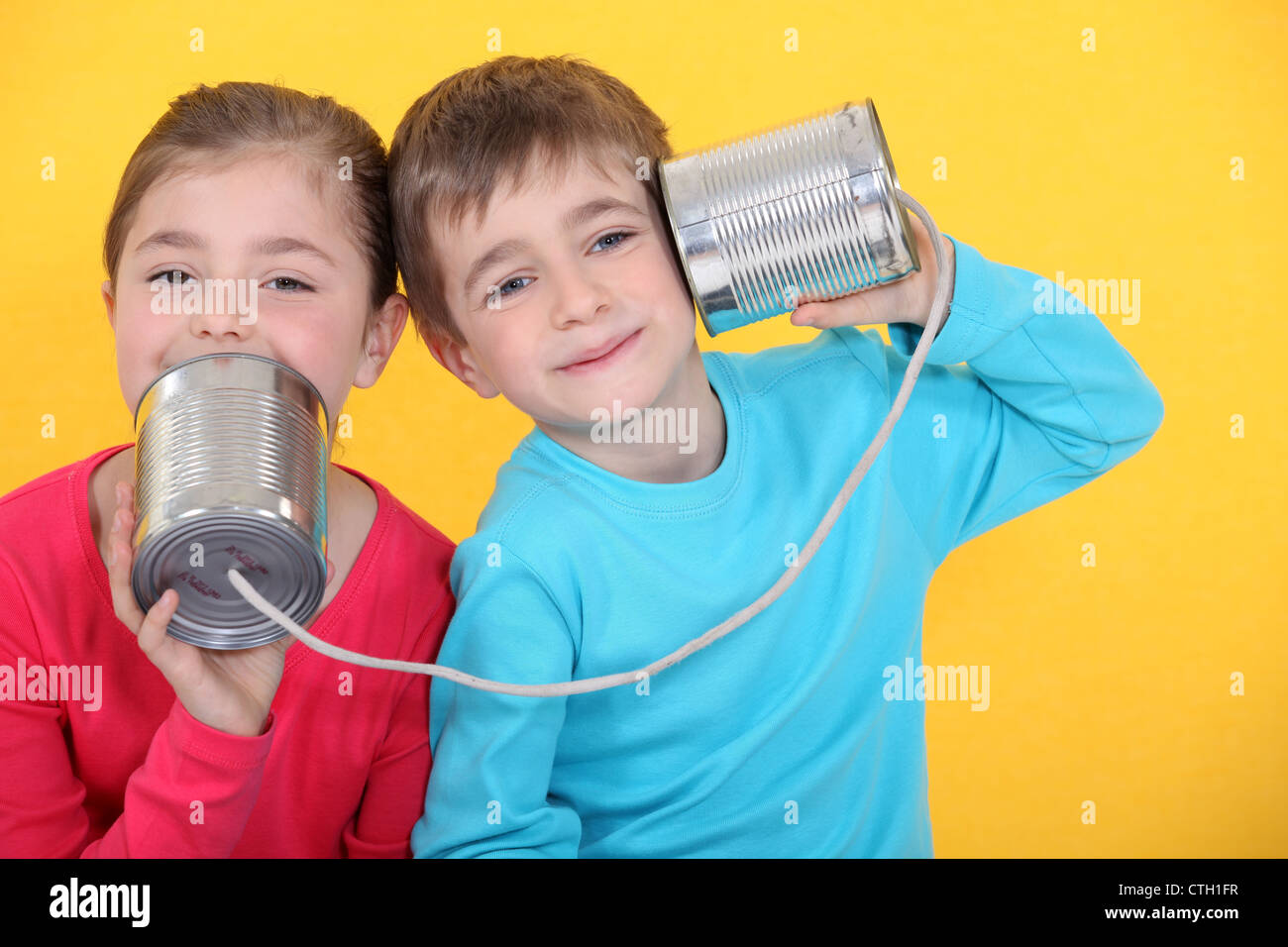 Kids having a phone call with tin cans on yellow background Stock Photo ...