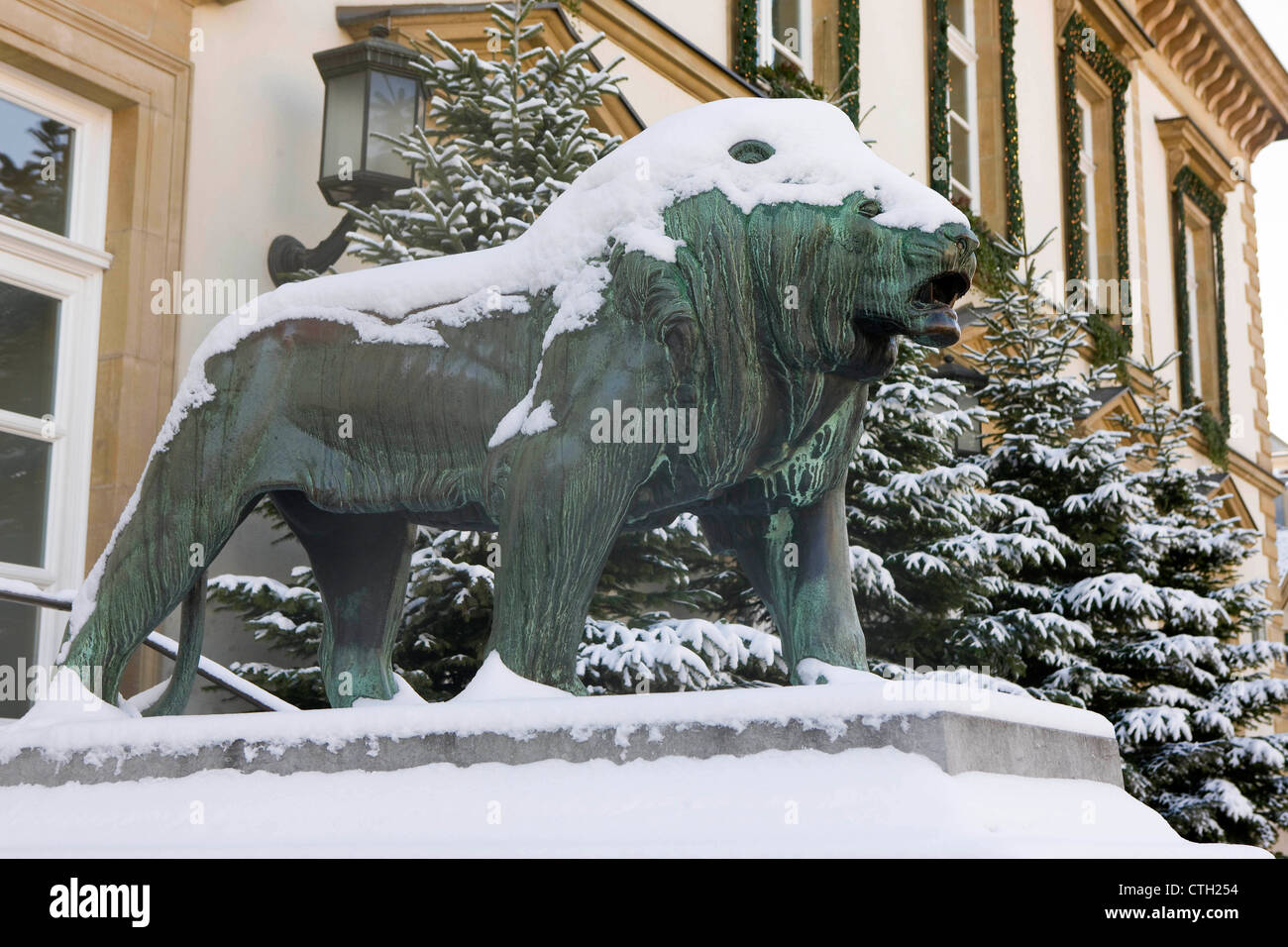 The bronze statue of a lion and Xmas trees covered with snow in front ...