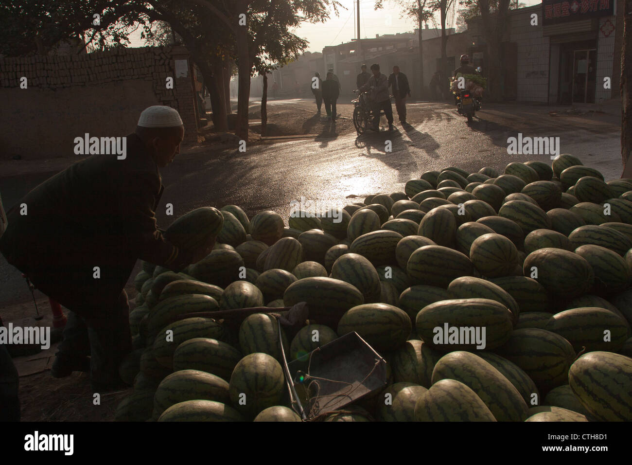 An Uighur man buys a watermelon from a stall in Turpan, Xinjiang, China ...
