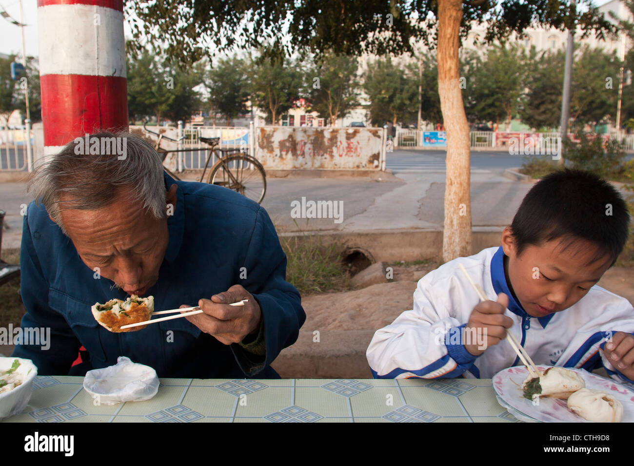 Han Chinese eat breakfast at an outdoor stall in Turpan, Xinjiang ...