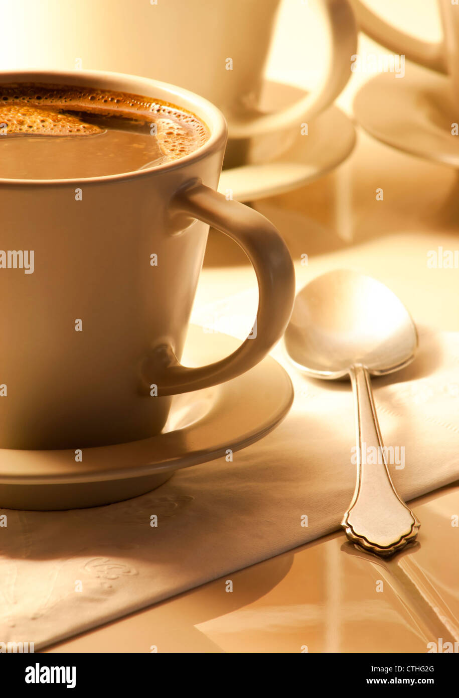 Cup of hot black espresso coffee with spoon and cups in background ...