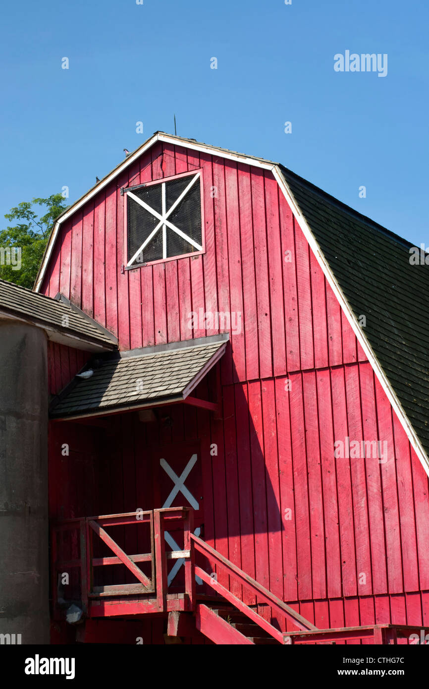 Bright red barn on rural farm against bright blue sky with copy space ...