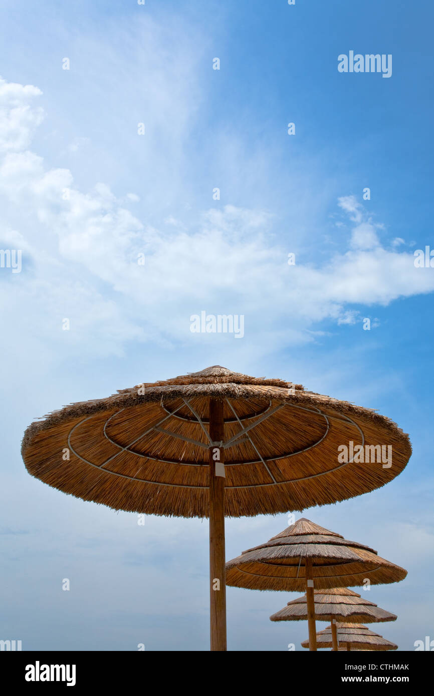 straw parasols and blue sky on San Marco beach near Taormina, Sicily ...