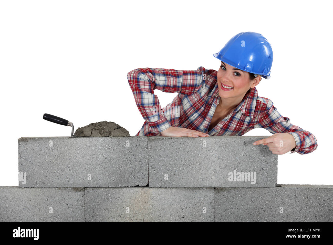 portrait of young female bricklayer pointing at concrete wall Stock ...