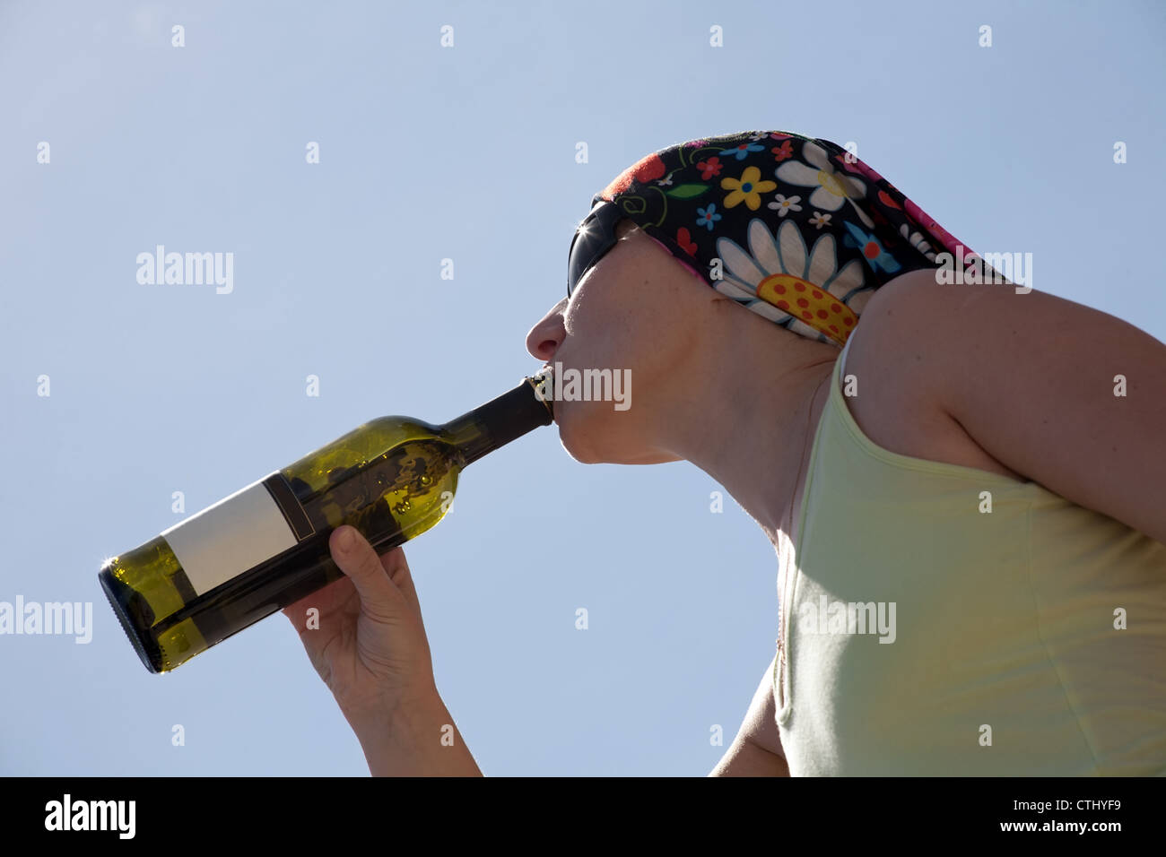profile of woman drinking from wine bottle on blue sky background Stock ...
