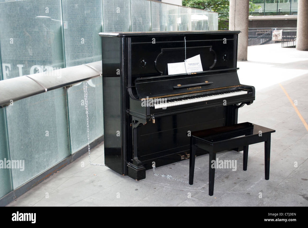 Piano on concrete walkway with glass barrier behind Stock Photo - Alamy