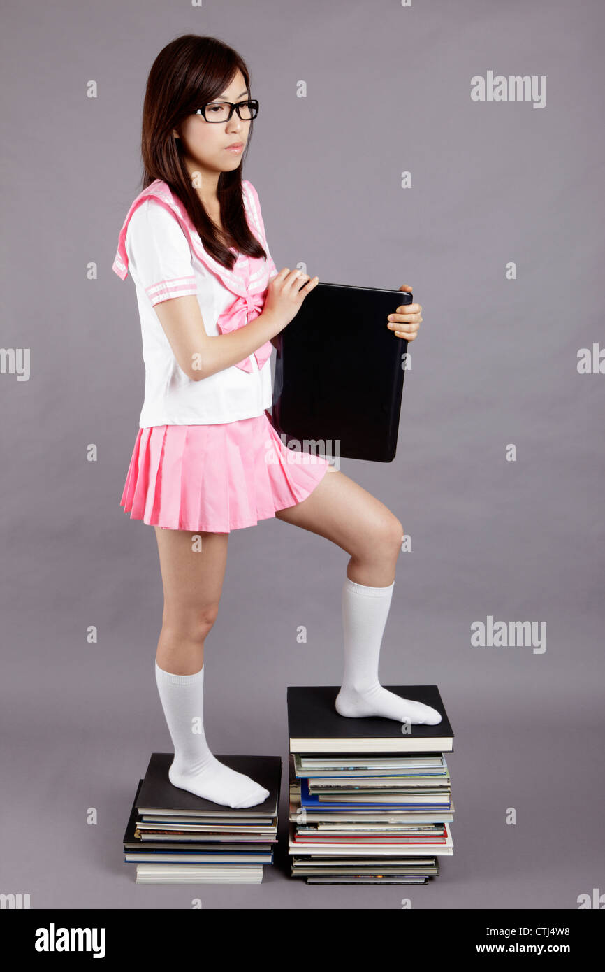 School girl uses notebook and stands on books Stock Photo - Alamy
