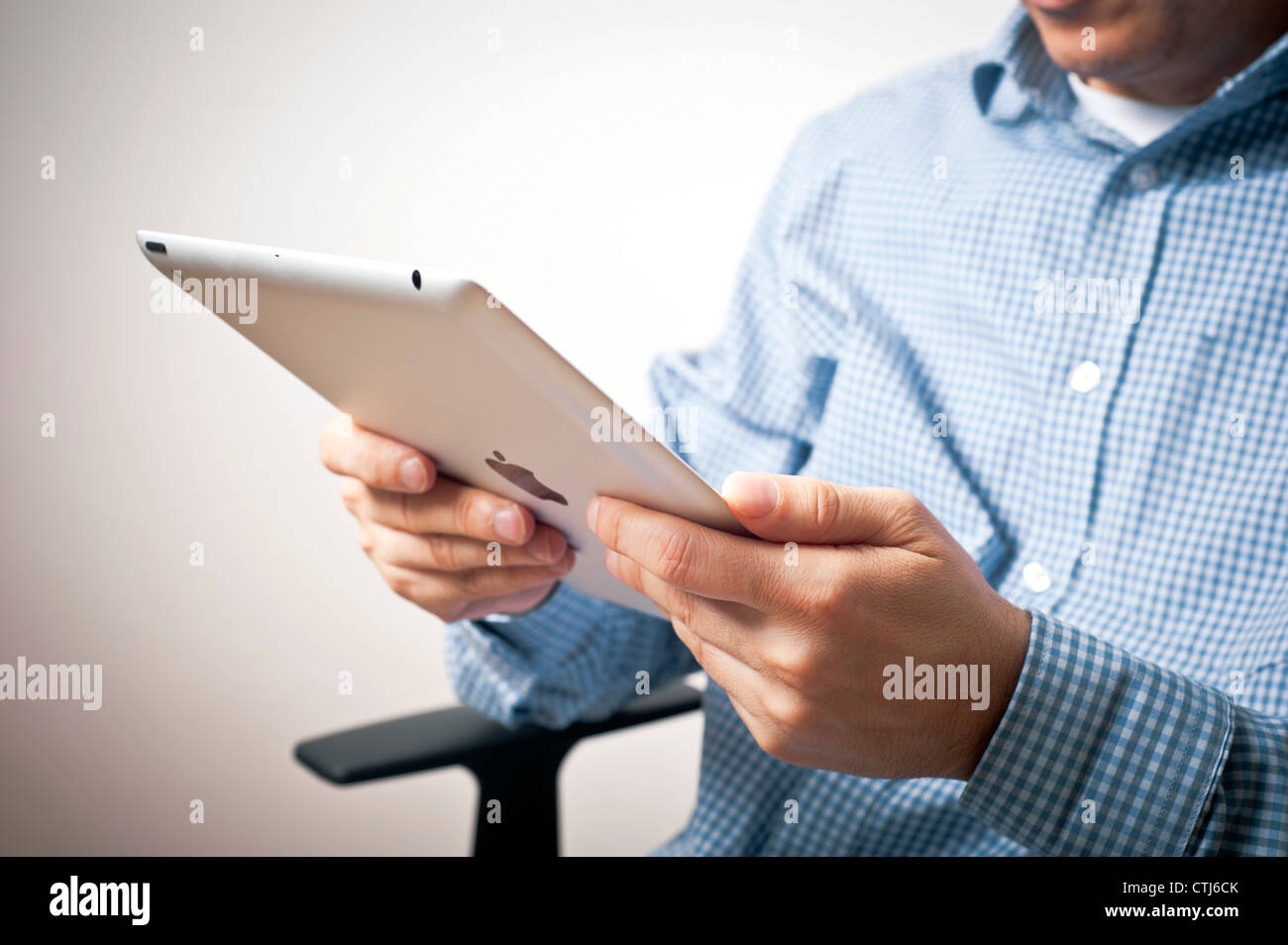 man sitting on a chair and using an iPad tablet Stock Photo - Alamy