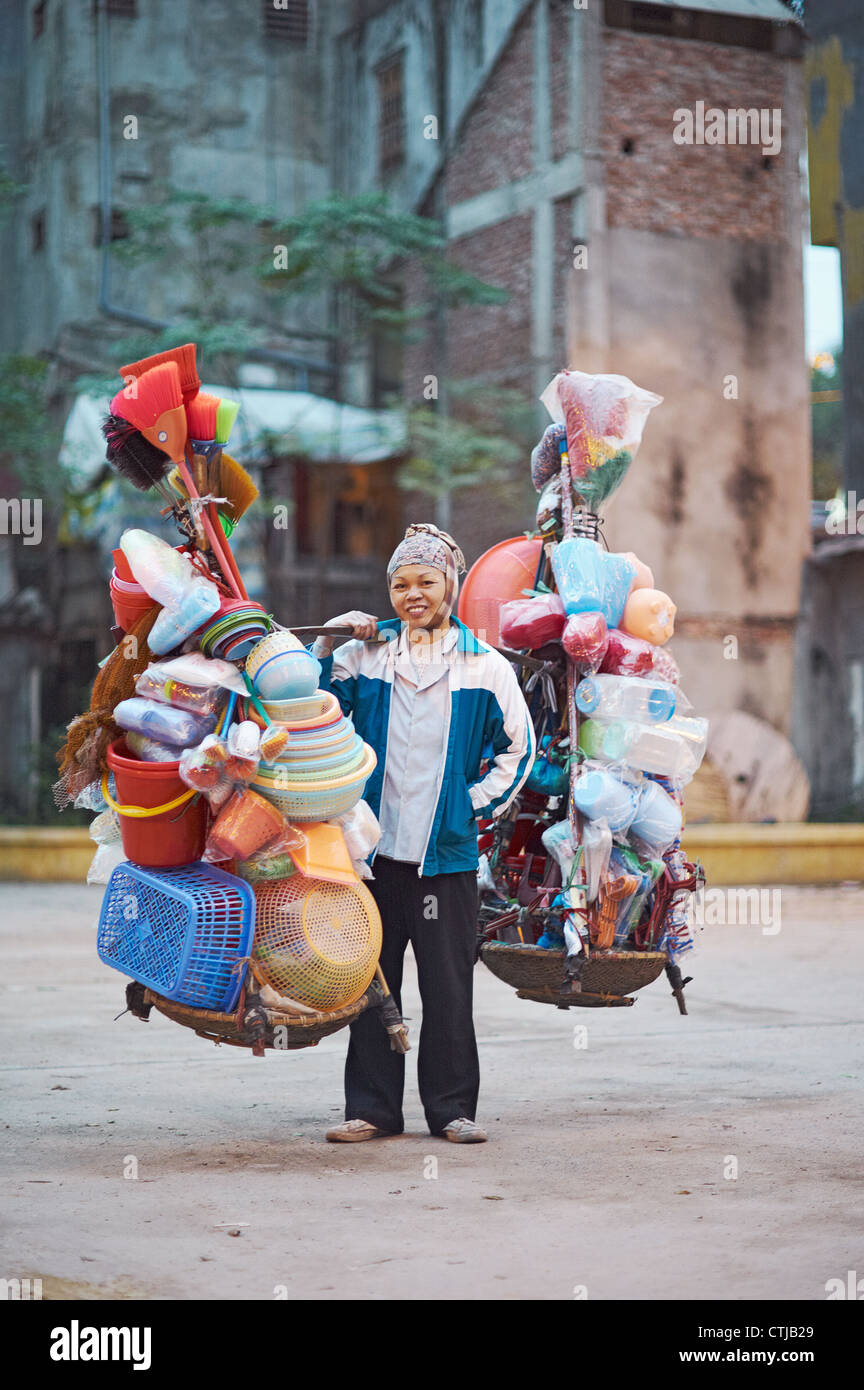 A woman selling plastic goods on the street balancing them on baskets ...