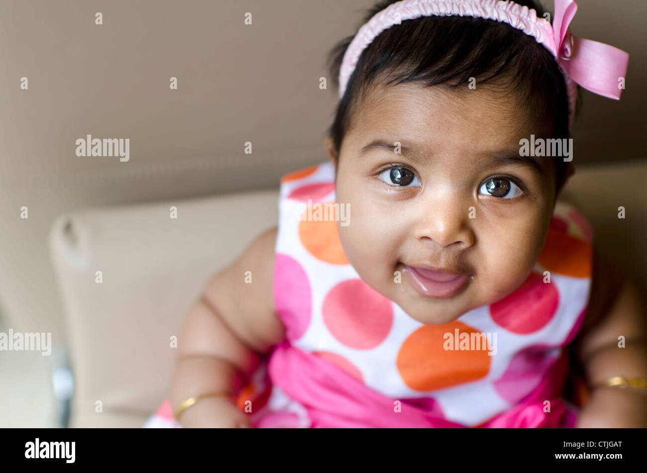 little indian baby girl resting on the arm of sofa seat, shallow dof ...
