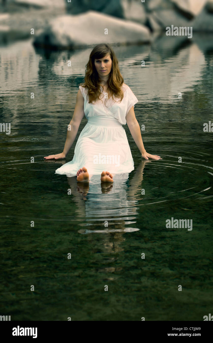a woman in a white dress sitting on the water Stock Photo - Alamy