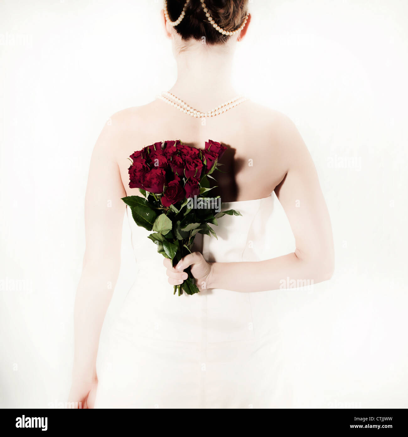 a woman in a white dress holding a bouquet of roses behind her back ...