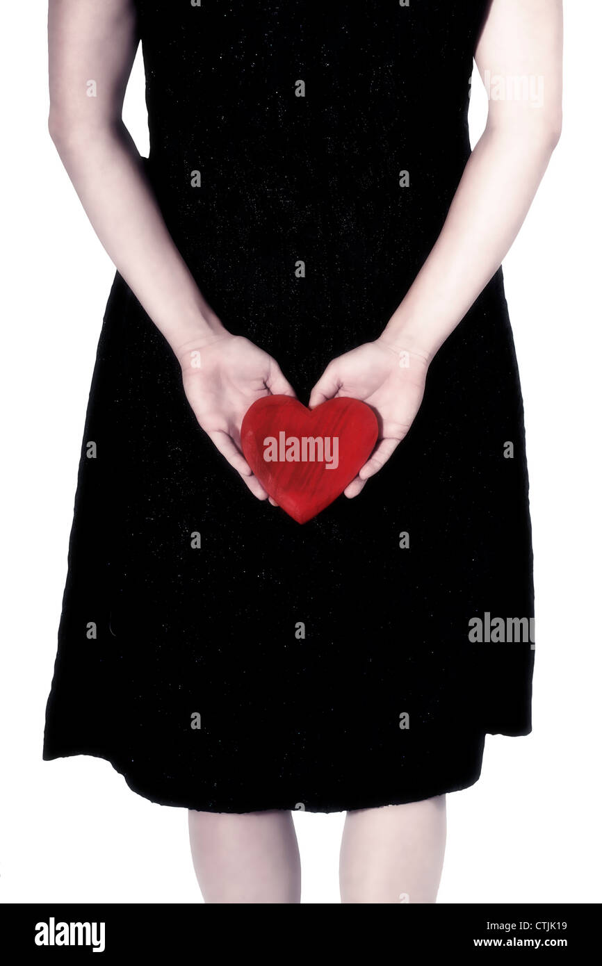 a woman in a black dress holding a red heart behind her back Stock ...