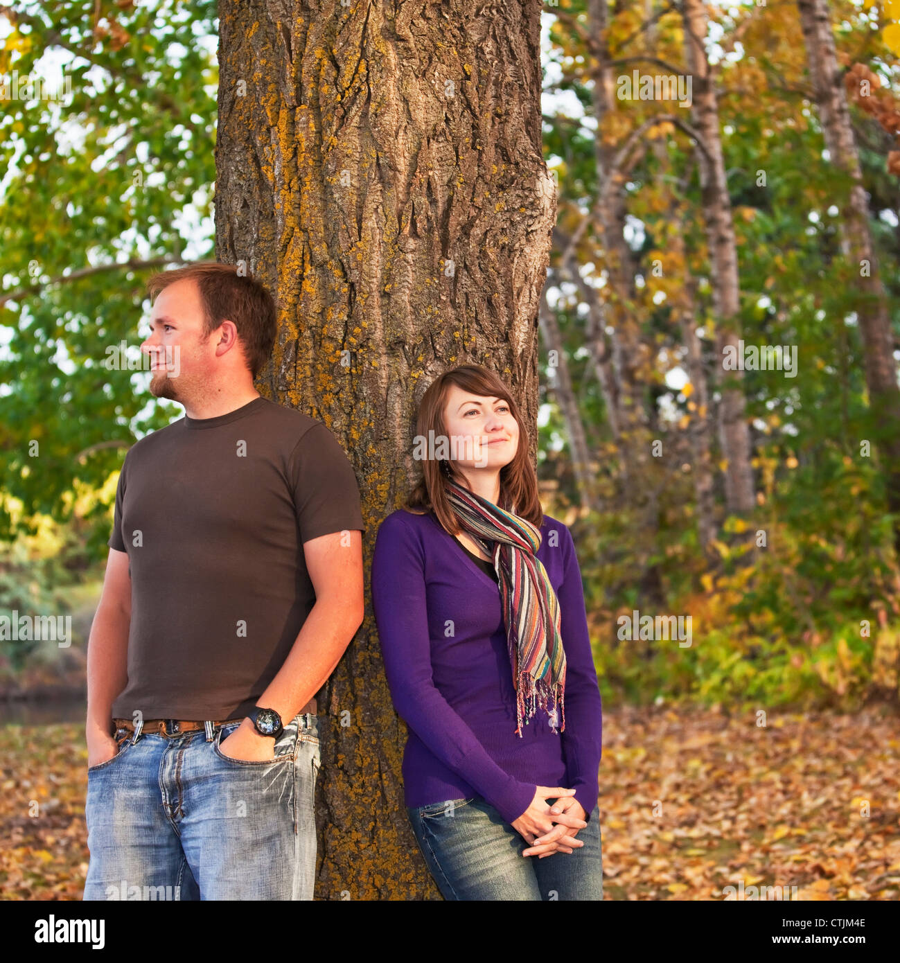 Young Married Couple Leaning Against A Tree In A Park In Autumn ...