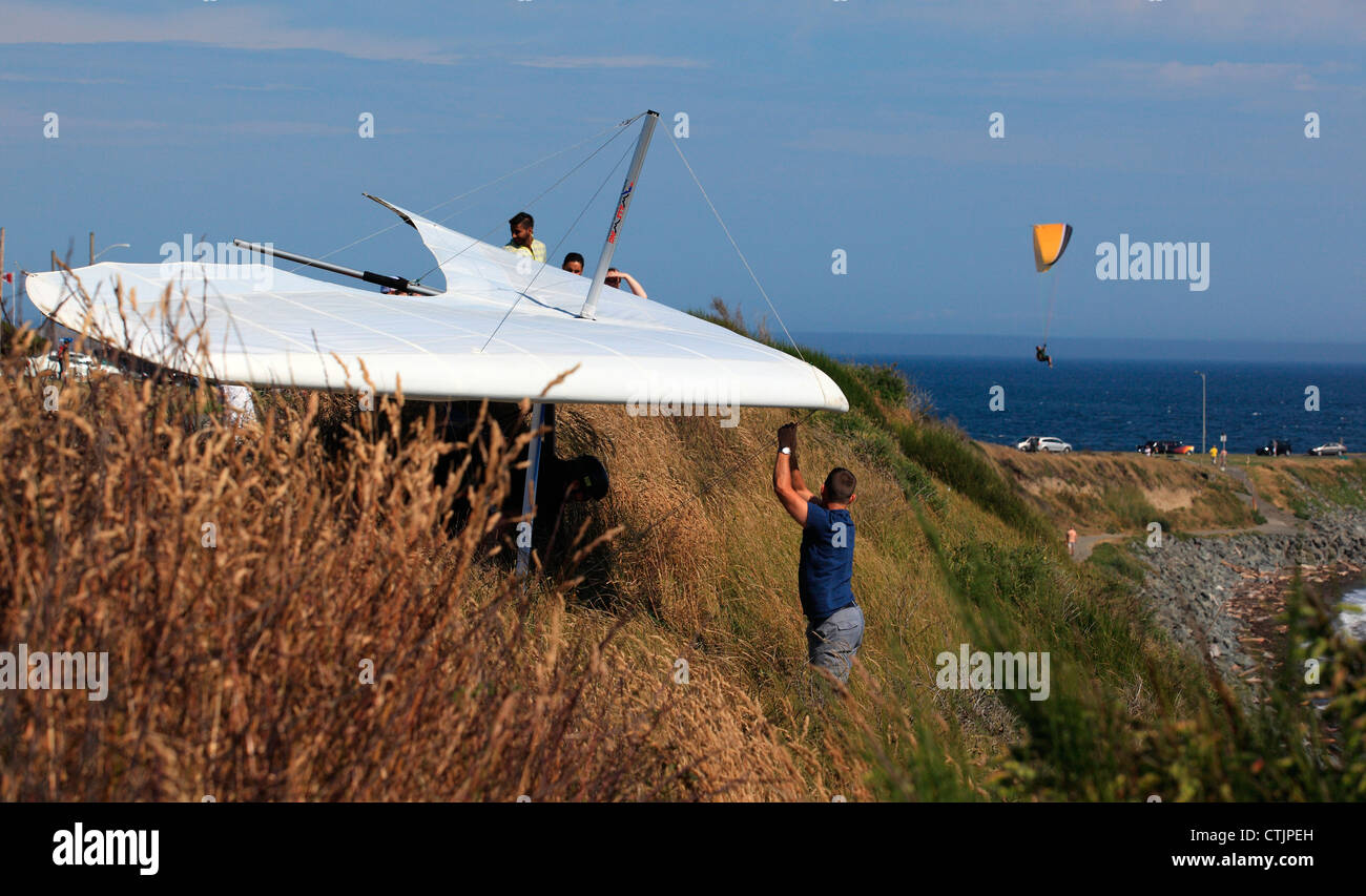 Man helping hang glider get ready to jump off cliff. People on cliff ...