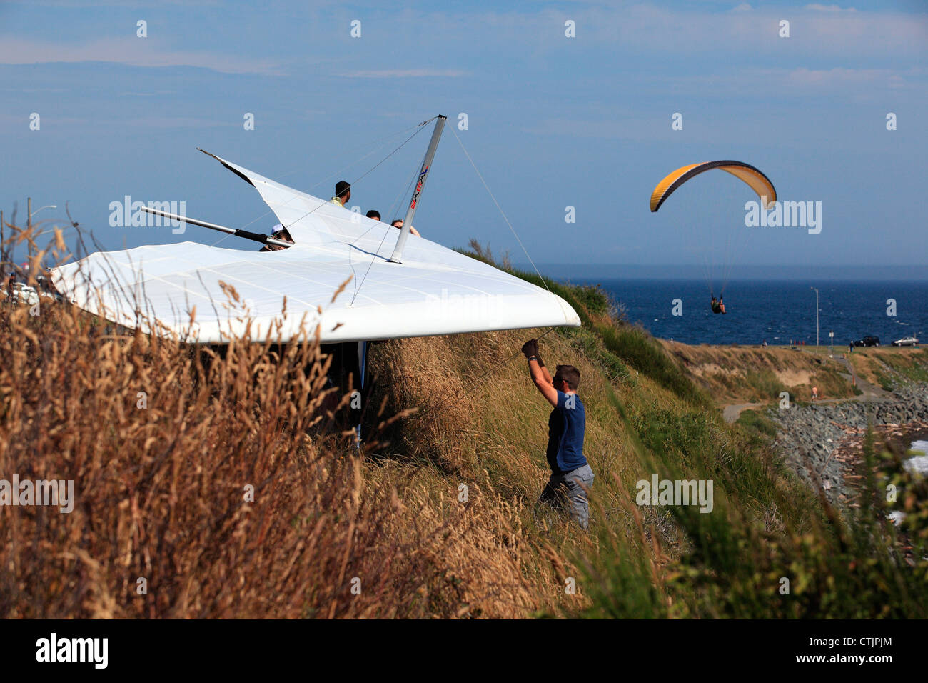 Man helping hang glider get ready to jump off cliff. Paraglider ...