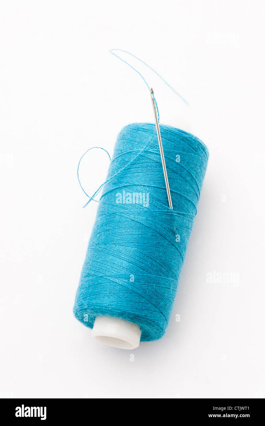 Threaded needle and spool of bright blue sewing thread Stock Photo - Alamy