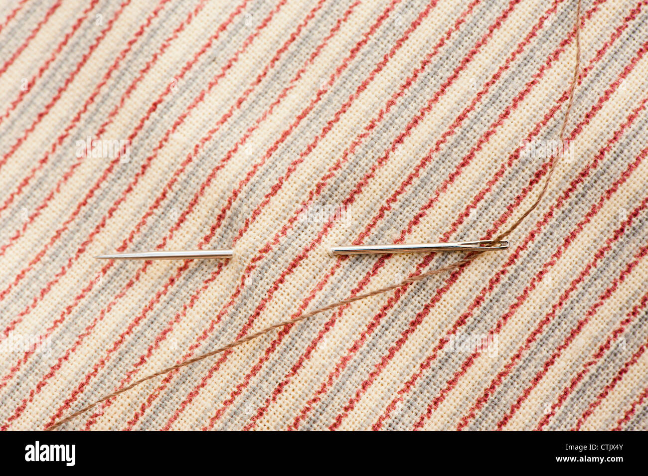 Threaded sewing needle in striped cloth Stock Photo - Alamy
