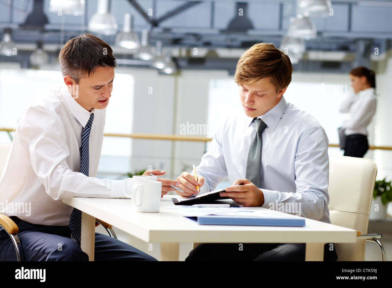 Senior businessman helping his younger colleague with financial ...