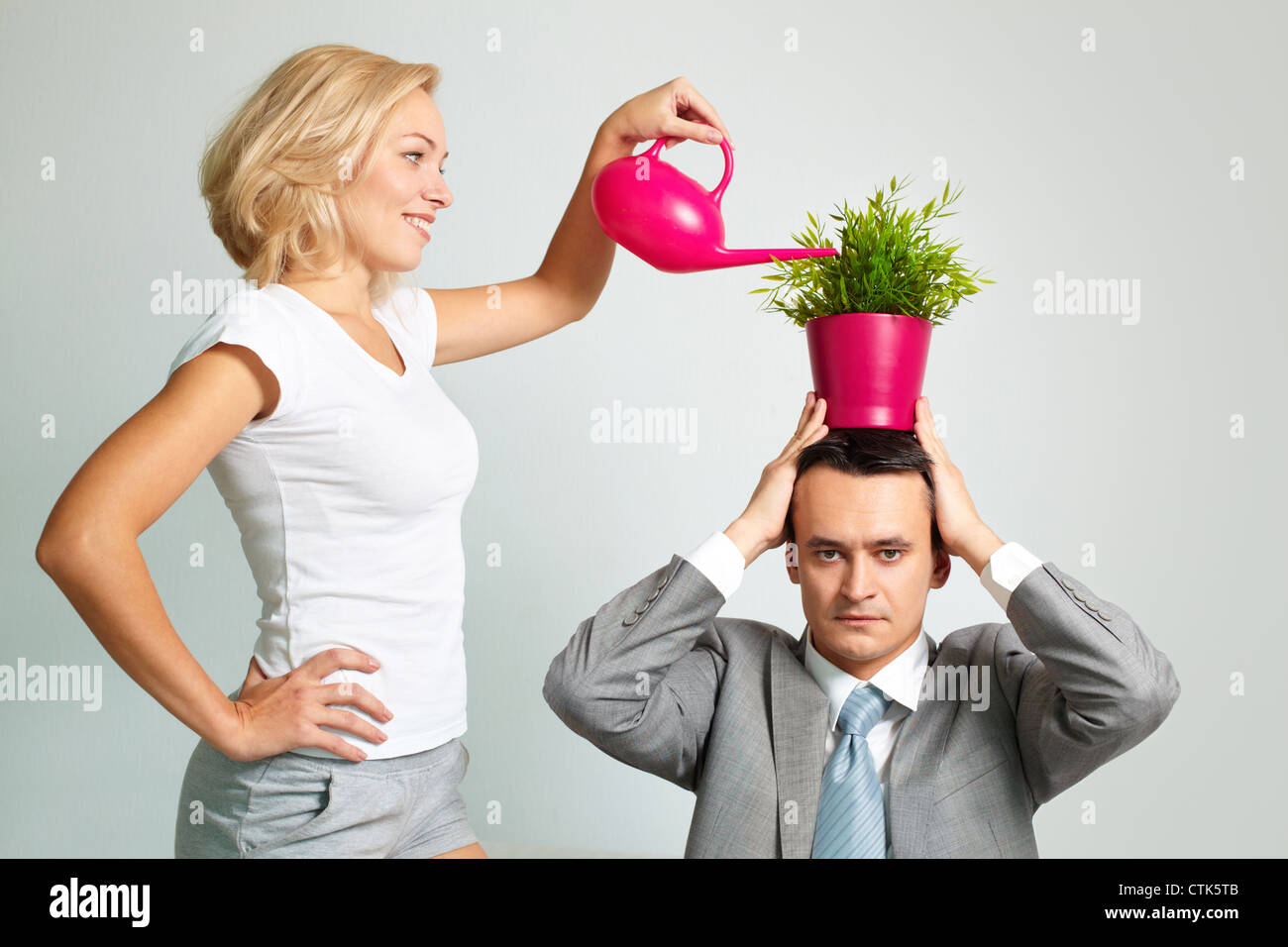 Young woman giving water to the plant on the head of the entrepreneur ...