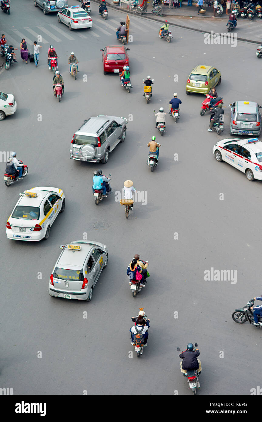 A busy intersection full of cars, trucks, scooters and people in Hanoi ...