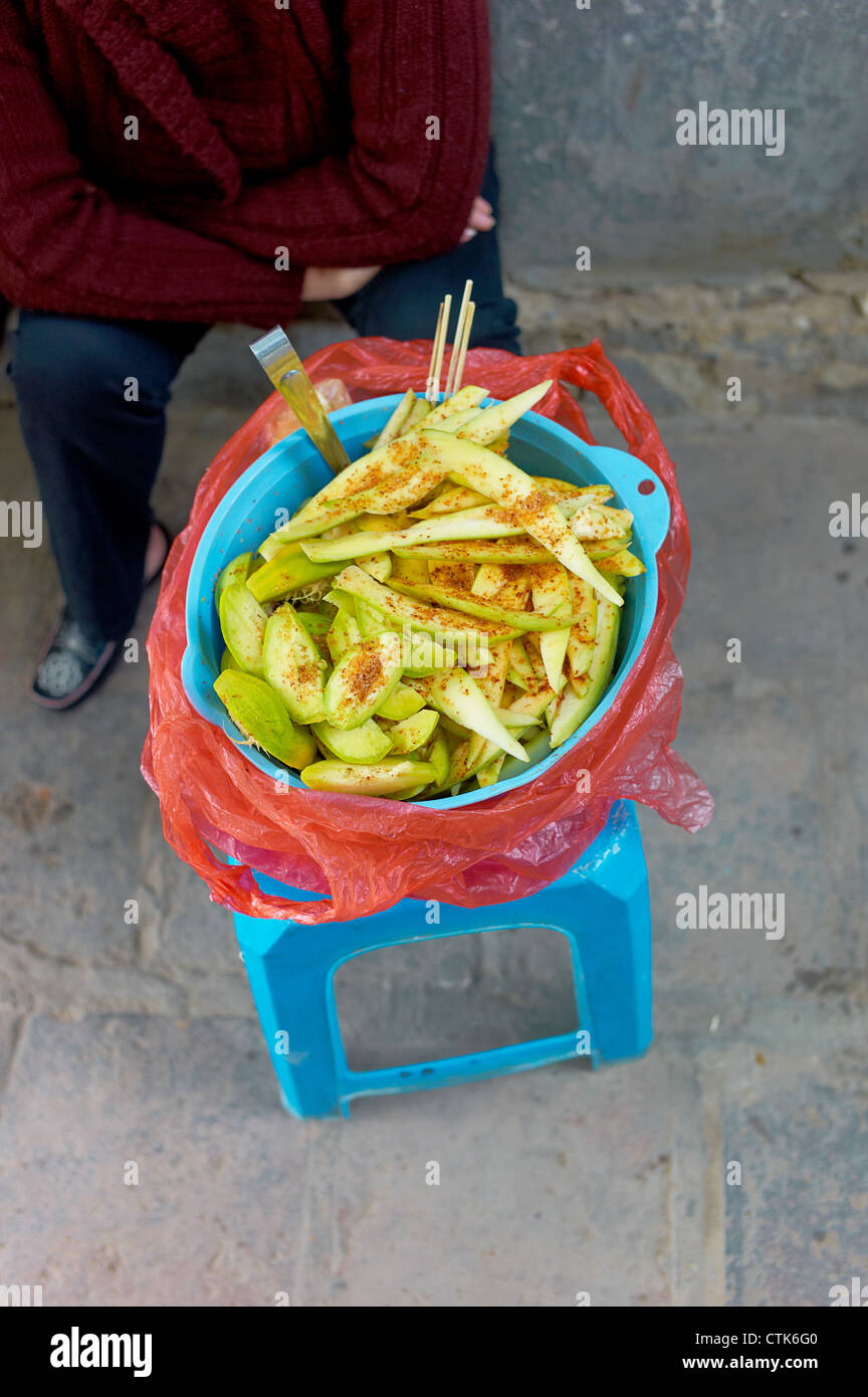 Fresh green mango with chili powder in a bucket being sold by a street ...