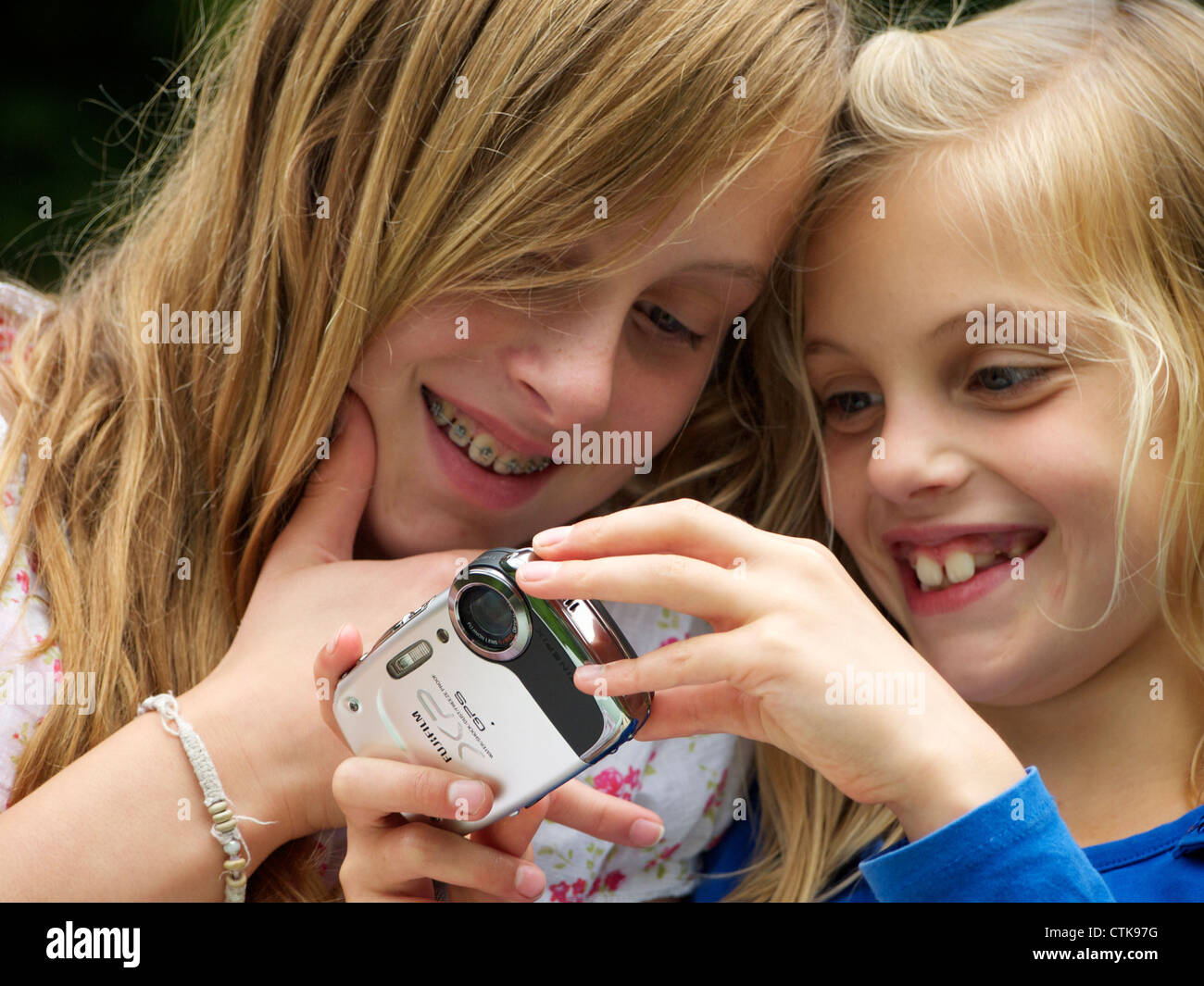Two young girls sisters smiling while looking at pictures on their ... Two young girls sisters smiling while looking at pictures on their ...