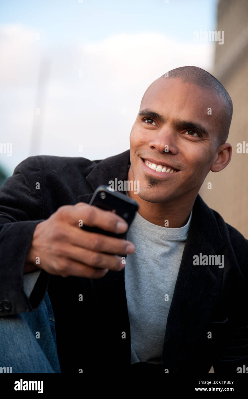 Happy man using cellphone and looking away with curiosity Stock Photo ...